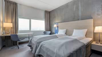 Quarto de hotel moderno com duas camas, uma escrivaninha e uma cadeira.