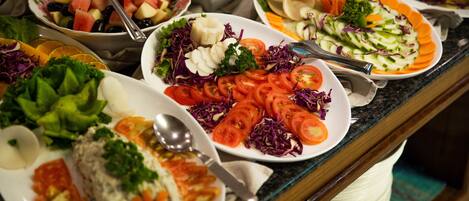 Buffet com diversos pratos, incluindo saladas, legumes e um prato com carne.