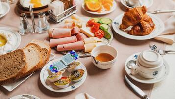 Uma mesa de café da manhã com diversos alimentos, como ovos, pão, queijo e frutas.