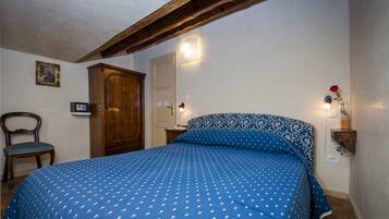 Quarto com cama, cadeira de madeira, guarda-roupa e luminárias fixadas na parede.