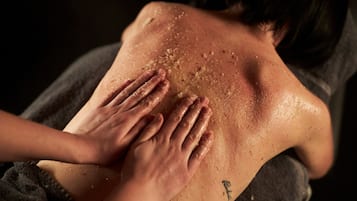 Close-up de mãos fazendo massagem nas costas de alguém.