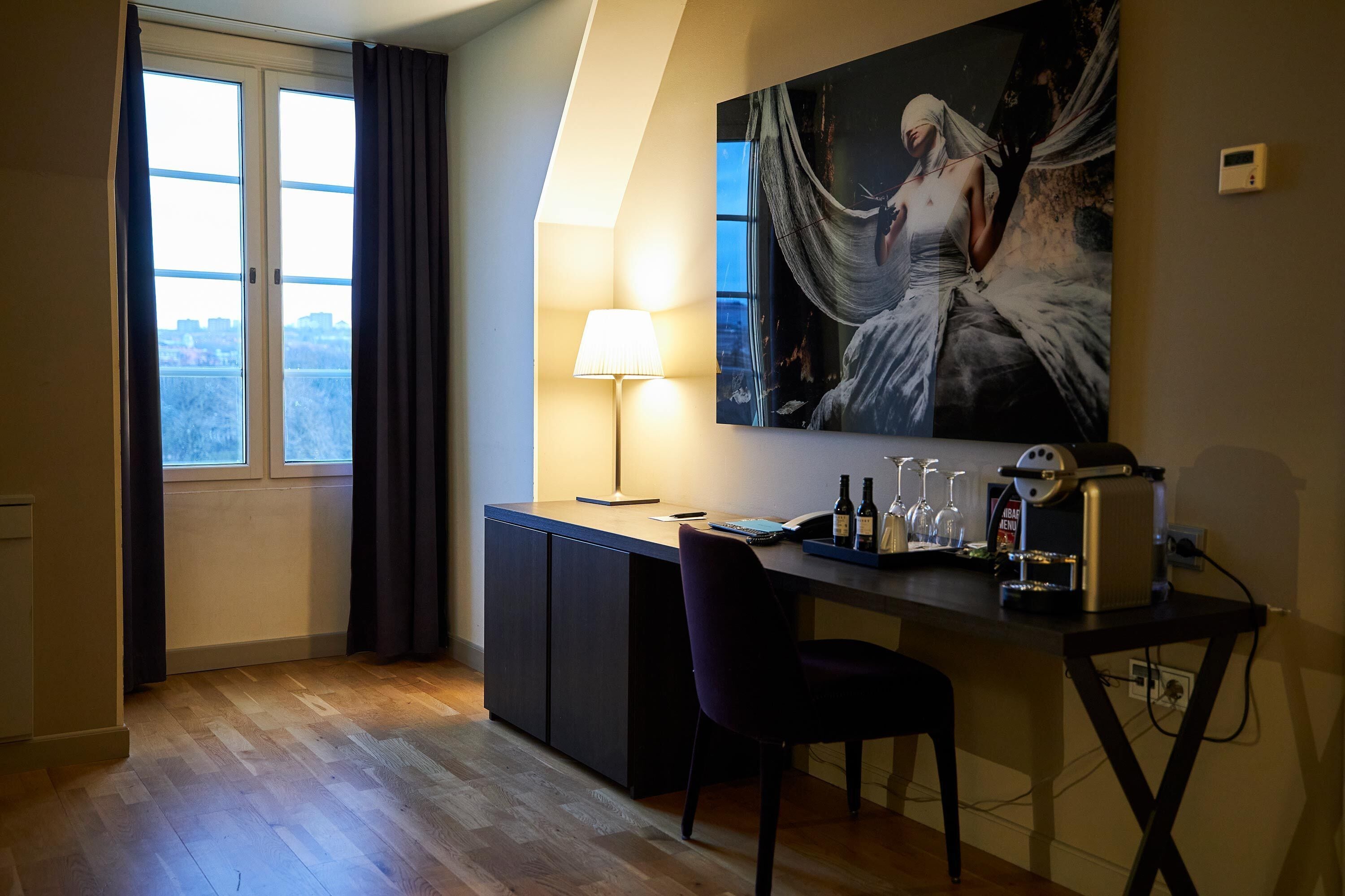 Quarto moderno com escrivaninha, cadeira e uma grande pintura.