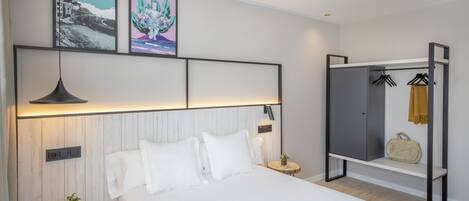 Quarto moderno com uma cama grande, mesas de cabeceira, guarda-roupa e uma obra de arte na parede.