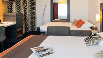 Quarto de hotel com uma cama, uma escrivaninha, uma cadeira, um abajur e um espelho.