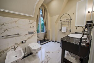 Casa de banho com lavatório de mármore, bidé, sanita e toucador com espelho e secador de cabelo.