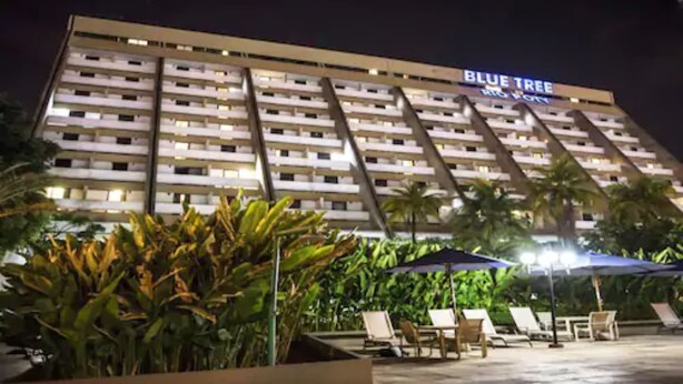 Um hotel com design moderno, com vários andares e uma placa chamativa com a inscrição "BLUE TREE HOTEL".