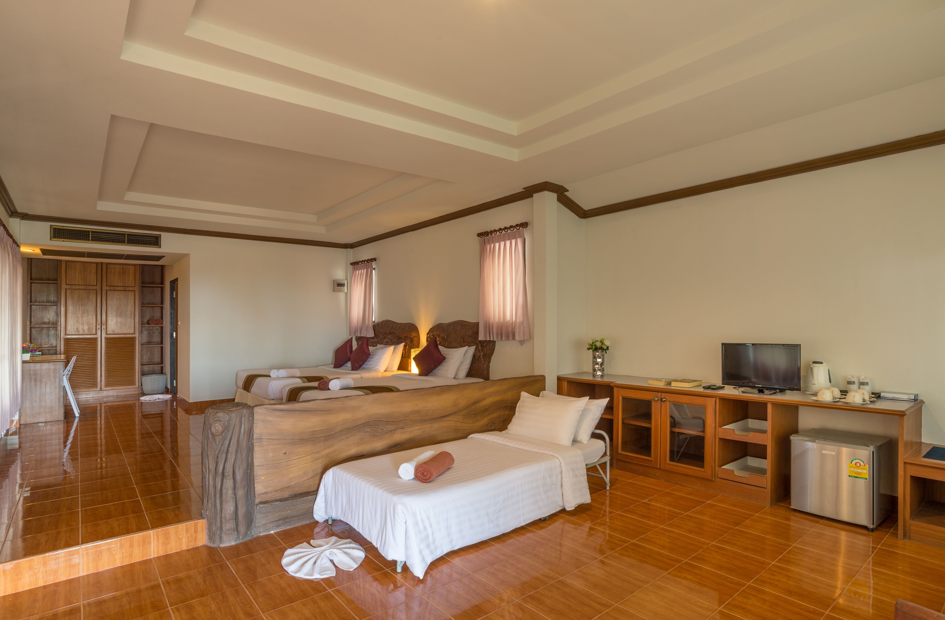 Um quarto espaçoso com uma cama grande, uma escrivaninha, uma televisão e um frigorífico.