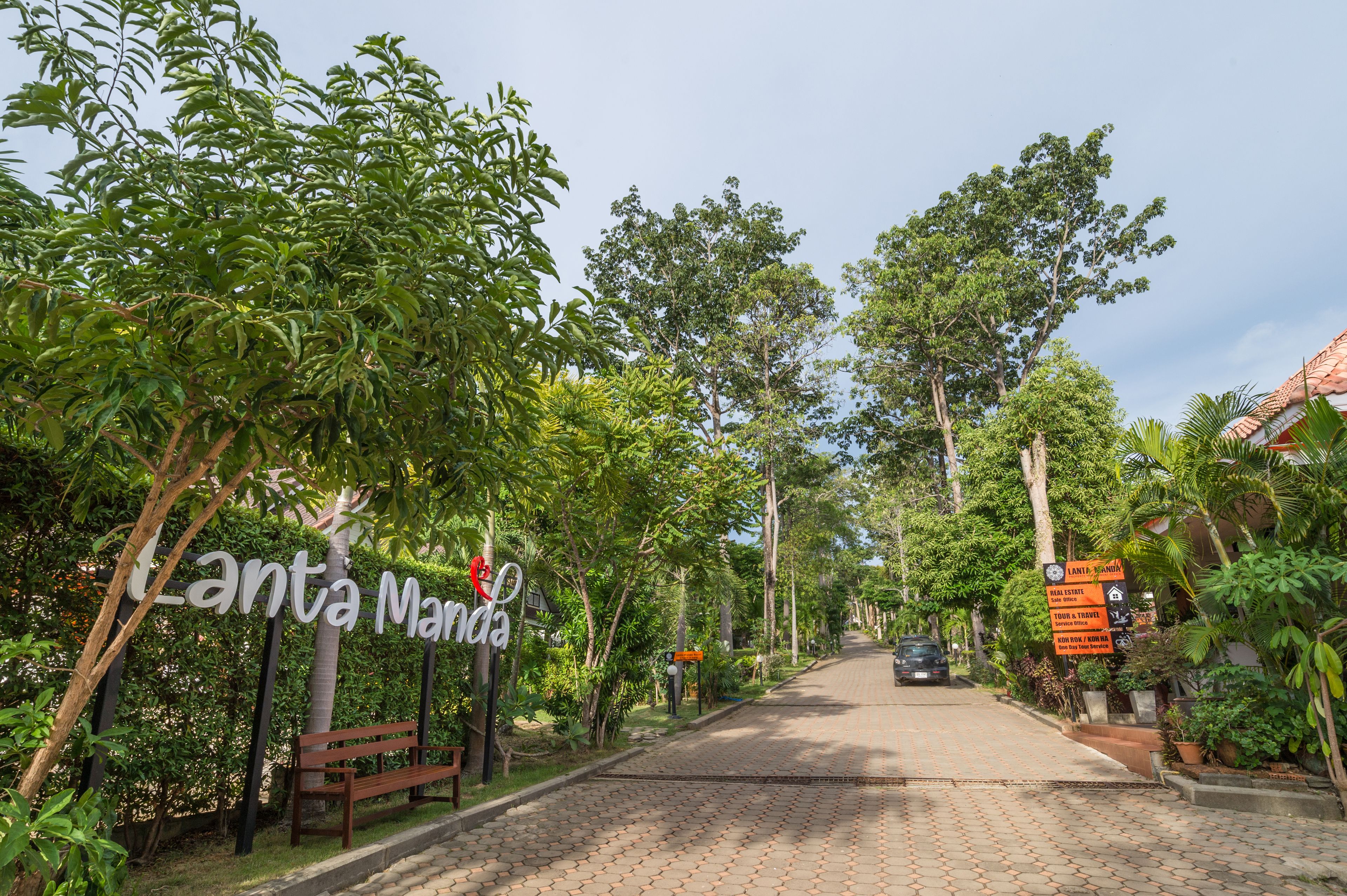 Uma rua pavimentada com um banco e uma placa com a inscrição 'Lanta Manda'.