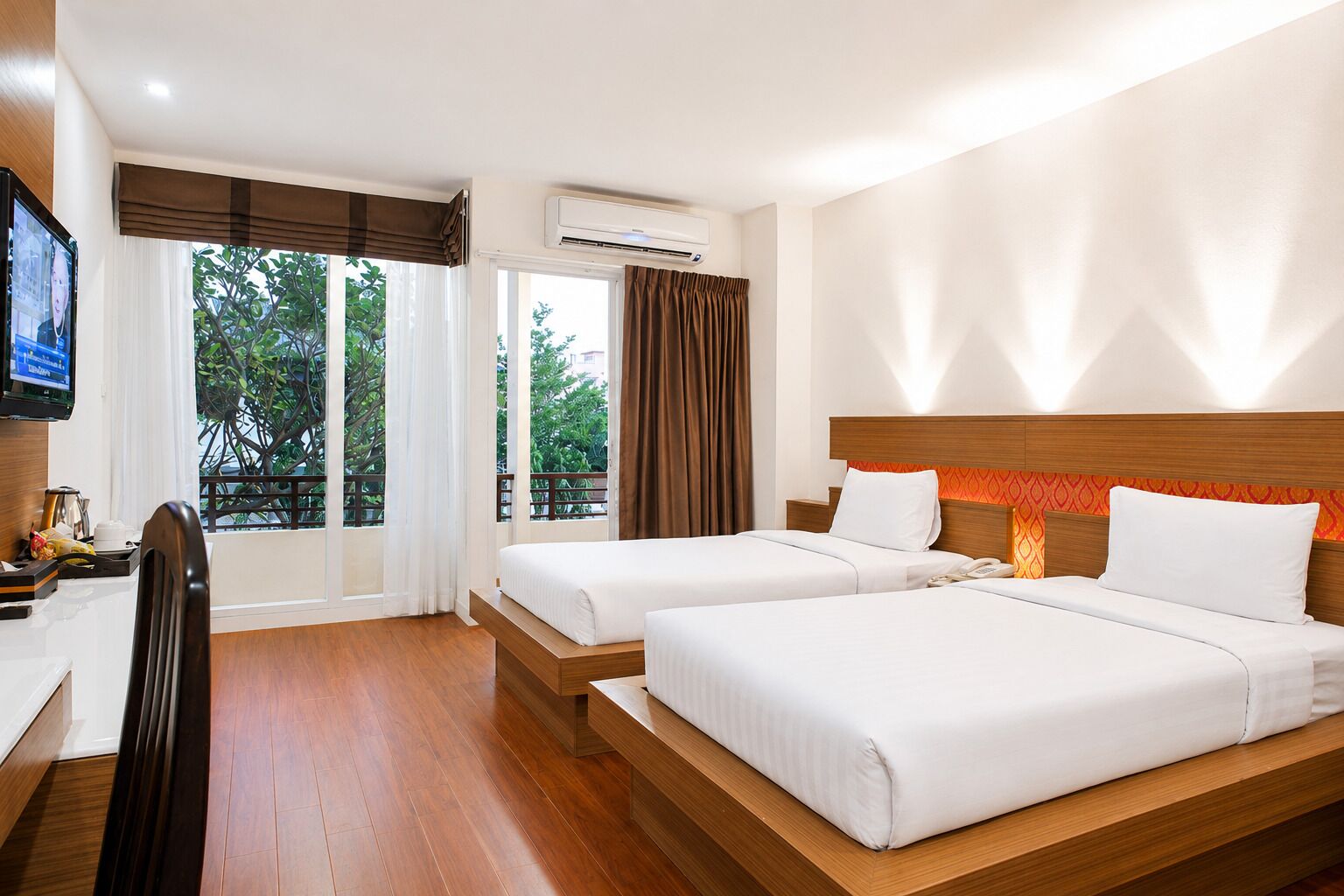 Quarto de hotel com duas camas, uma escrivaninha e uma televisão.