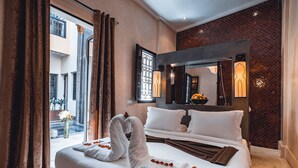 Quarto de hotel com uma cama grande, vista para a cidade e uma varanda com cortinas.