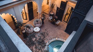 Um pátio com piscina, áreas de estar e vista para o interior.