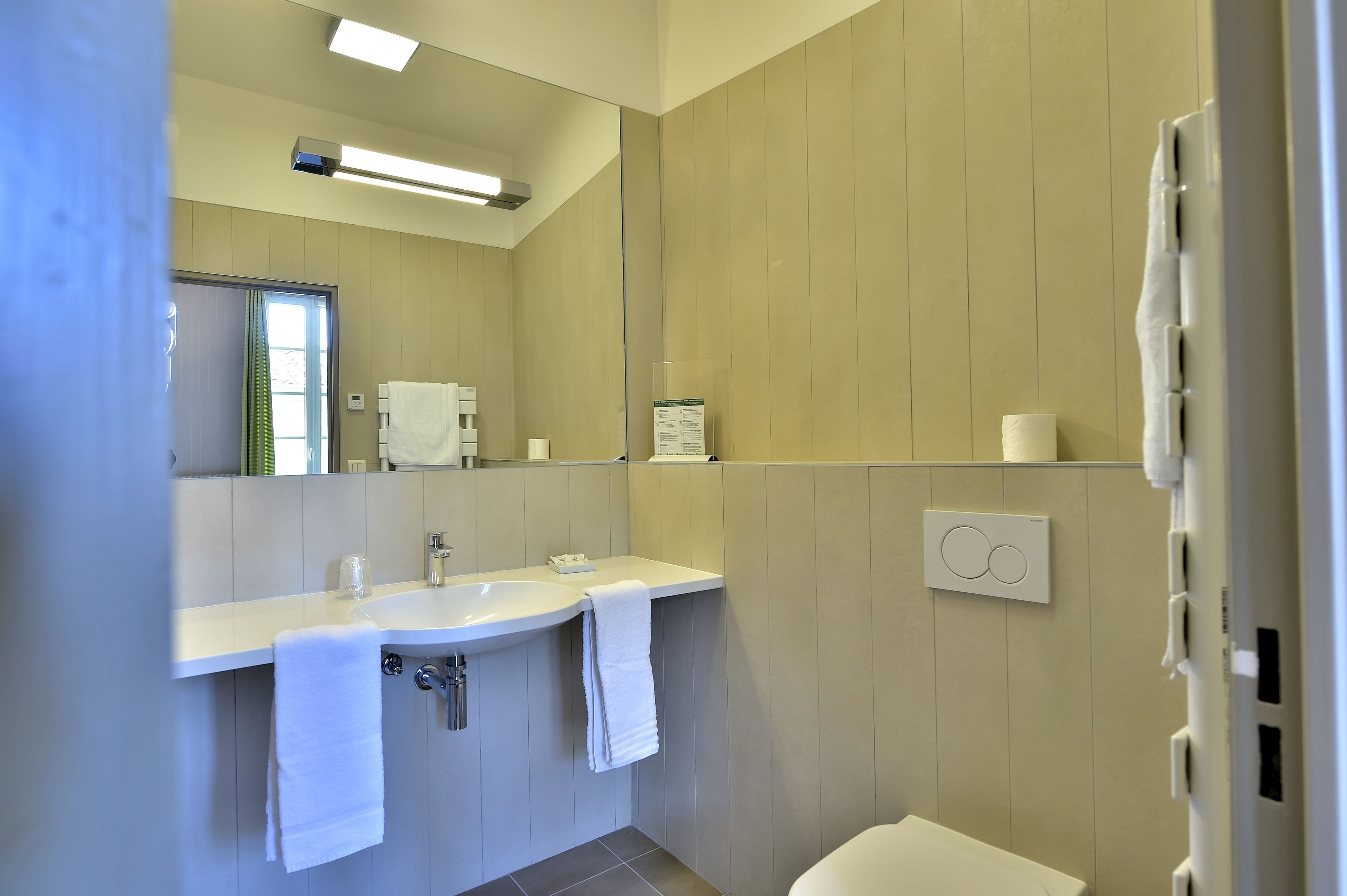Uma casa de banho moderna com lavatório, espelho e porta-toalhas.