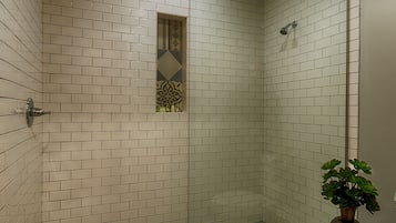 Um chuveiro com porta de vidro, paredes revestidas de azulejos e piso estampado.