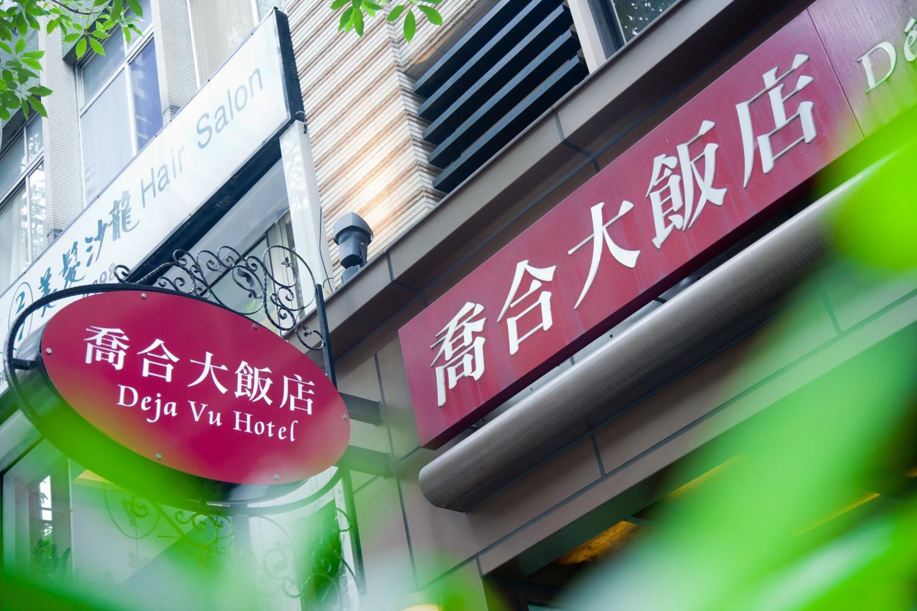 Placa de hotel com caracteres chineses e o texto em inglês 'Deja Vu Hotel'.