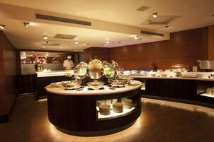 Uma mesa de buffet com várias estações de serviço, um chef preparando comida e uma variedade de pratos à mostra.