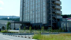 Um hotel de vários andares com design moderno, destacando uma entrada imponente e uma série de varandas.