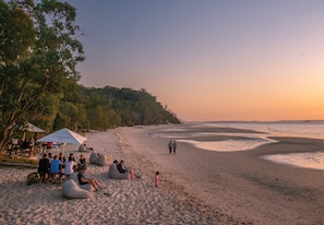 Na praia, espreguiçadeiras, guarda-sóis, toalhas de praia 