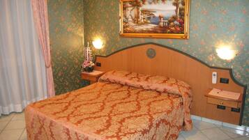 Quarto com cama, mesas de cabeceira, um quadro e luminária na parede.