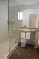 Uma casa de banho moderna com chuveiro envidraçado, lavatório com bancada de mármore e sanita.
