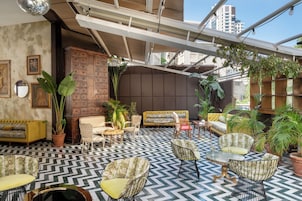 Uma área de estar aconchegante em ambiente interno, com piso estampado, móveis de madeira e plantas em vasos.