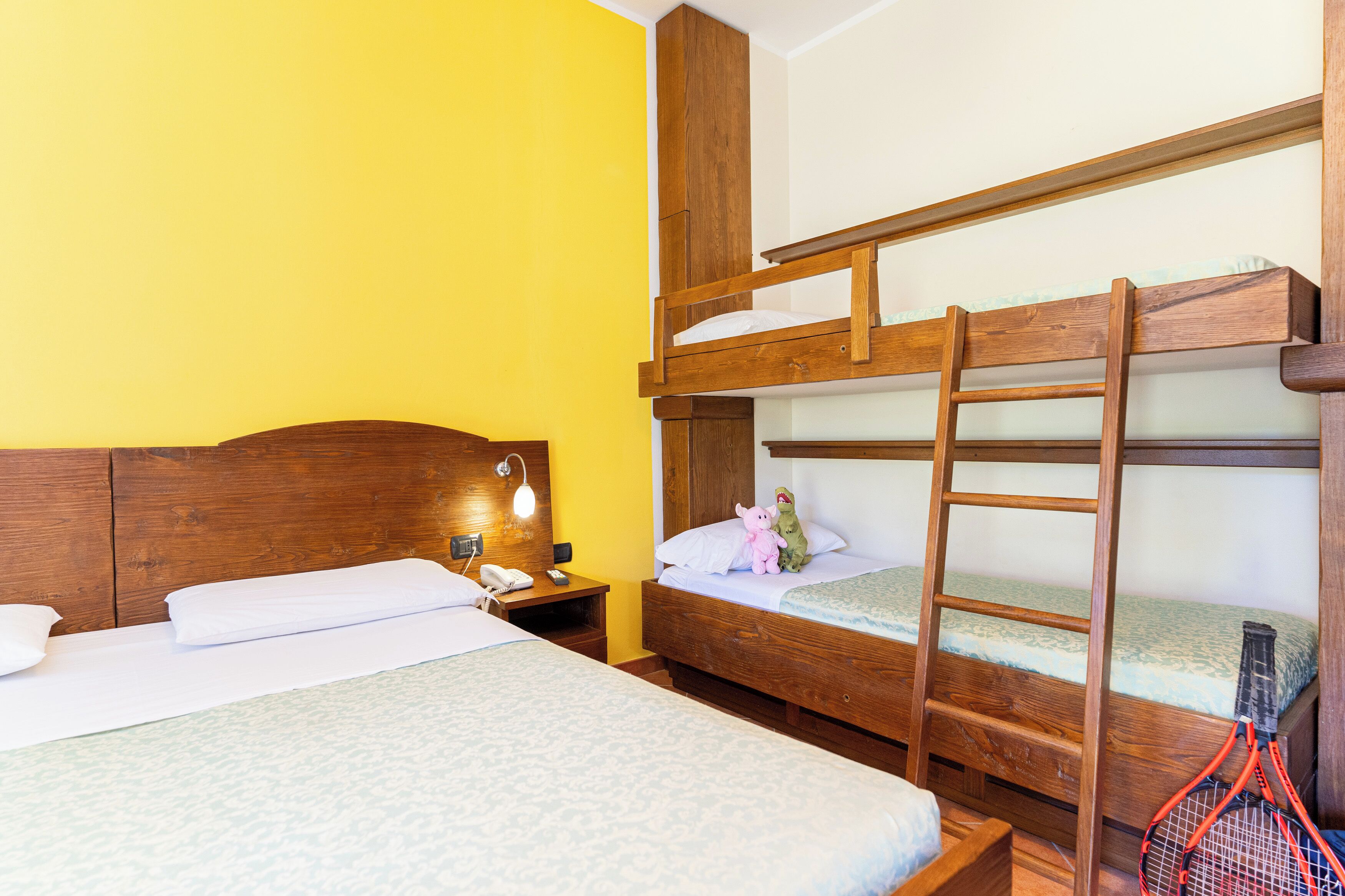 Quarto com uma cama de solteiro, uma cama individual e uma mesa de cabeceira com abajur.