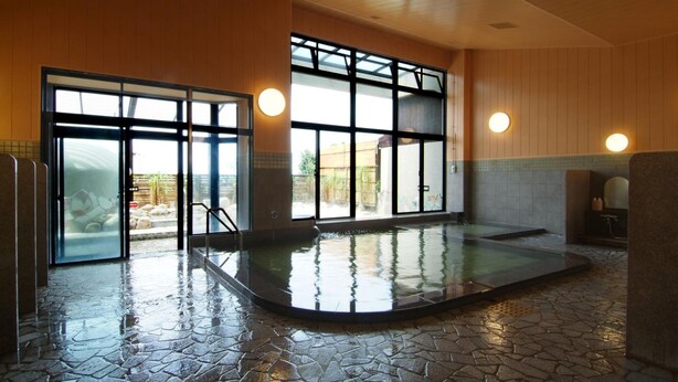 Área de spa com piso de pedra, grandes janelas e piscina.