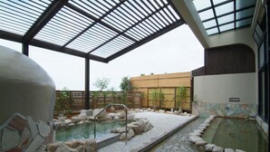 Uma área de spa com piscina, ladrilhos de pedra e cerca de madeira.