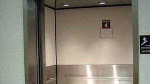 Interior de elevador com acabamento metálico, sinalização indicando o quarto andar, e símbolo de acessibilidade para cadeiras de rodas.