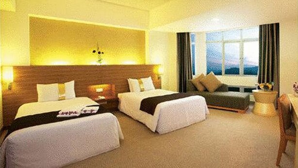 Quarto de hotel com duas camas, um sofá, uma janela com cortinas e um ventilador de teto.