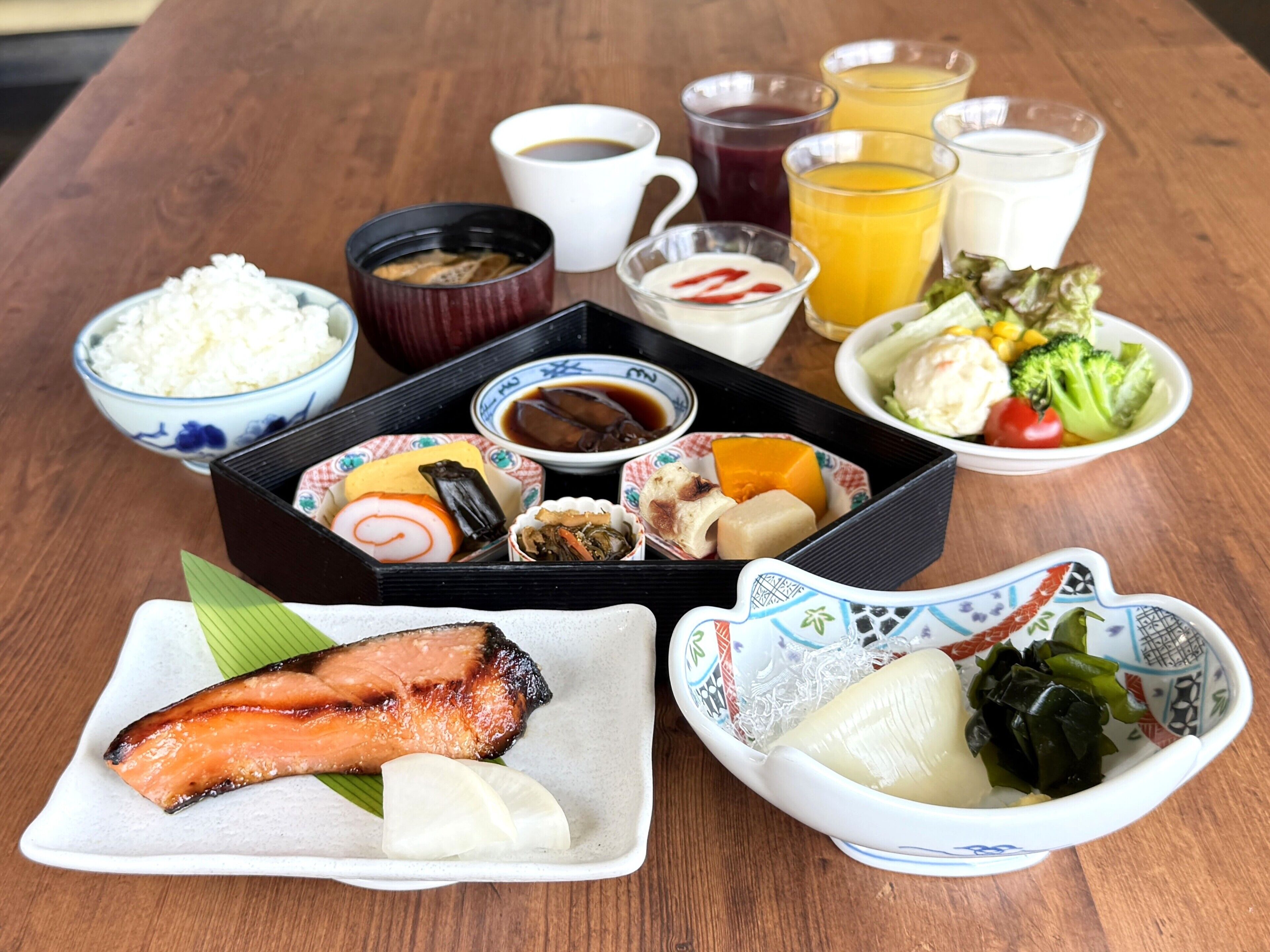 Uma refeição tradicional japonesa com vários pratos e bebidas sobre uma mesa de madeira.