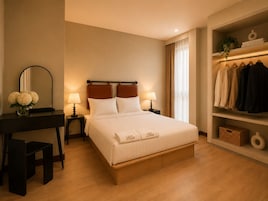 Quarto de hotel com cama, mesas de cabeceira, espelho, escrivaninha e guarda-roupa.