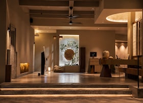 Interior moderno com um elemento central de água, um ventilador de teto e um balcão de recepção.