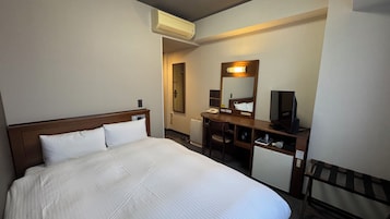 Quarto de hotel com cama, escrivaninha, cadeira, televisão e ar condicionado.