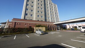 Um edifício com vários andares e um estacionamento na frente.