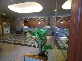 Um saguão com uma receção, uma máquina de vendas automática e um balcão de check-in.
