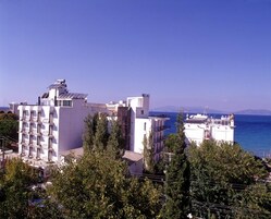 Um hotel à beira-mar com vários edifícios brancos, alguns com varandas, e vista para o mar.