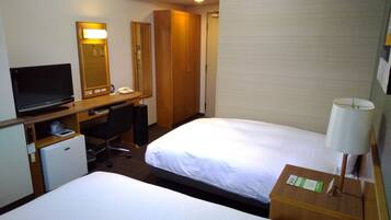 Quarto de hotel com duas camas, uma escrivaninha com computador, televisão, telefone e ar condicionado.