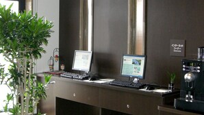 Um balcão de recepção com dois monitores de computador, um teclado e uma máquina de café. Há plantas em vasos em ambos os lados do balcão.