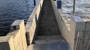 Um cais de concreto que se estende sobre a água, com um farol no final.