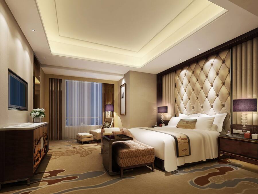 Quarto de hotel espaçoso com uma cama grande, área de estar, mesa de trabalho e uma janela ampla com cortinas.