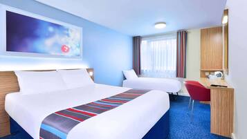 Quarto de hotel com uma cama grande, uma escrivaninha com cadeira, televisão e janela com cortinas.