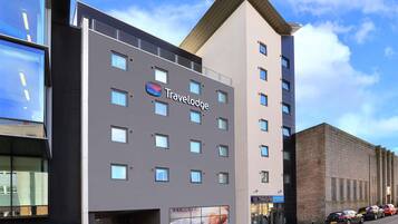 Um hotel Travelodge com design moderno, destacando um logotipo proeminente e várias janelas.