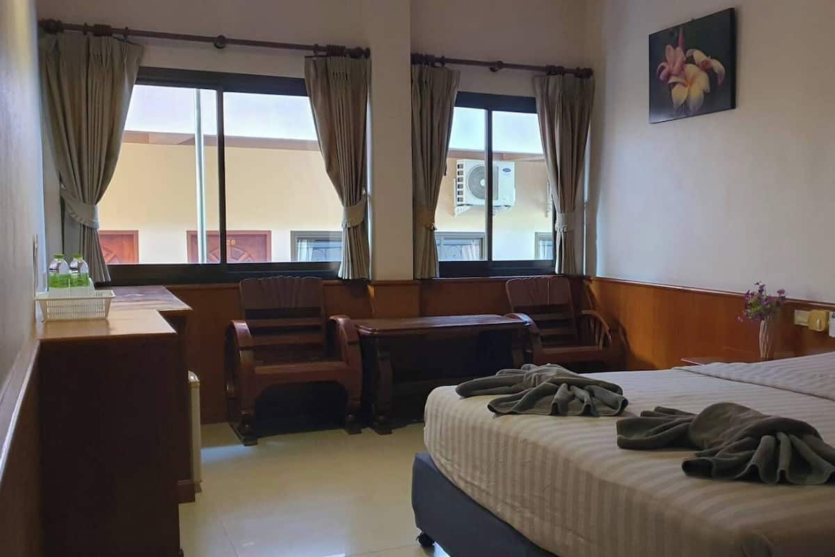 Quarto de hotel com cama, escrivaninha, cadeira e janela com cortinas.