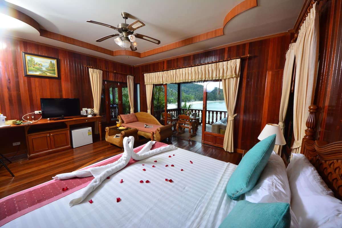 Quarto de hotel com cama, escrivaninha, televisão e vista para o oceano.