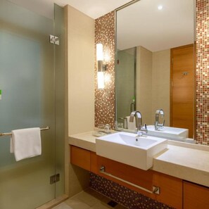 Uma casa de banho moderna com duas pias, cabine de duche em vidro e um espelho grande.