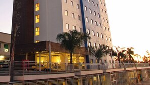Um hotel moderno com um letreiro chamativo 'one hotel', vários andares e uma área de estacionamento com entrada coberta.