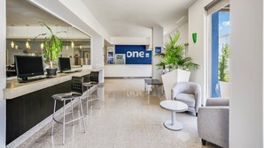 Uma área de recepção moderna com balcão, computadores e assentos.