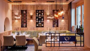 Um restaurante com decoração em madeira, área de bar com garrafas e disposição de mesas e cadeiras.