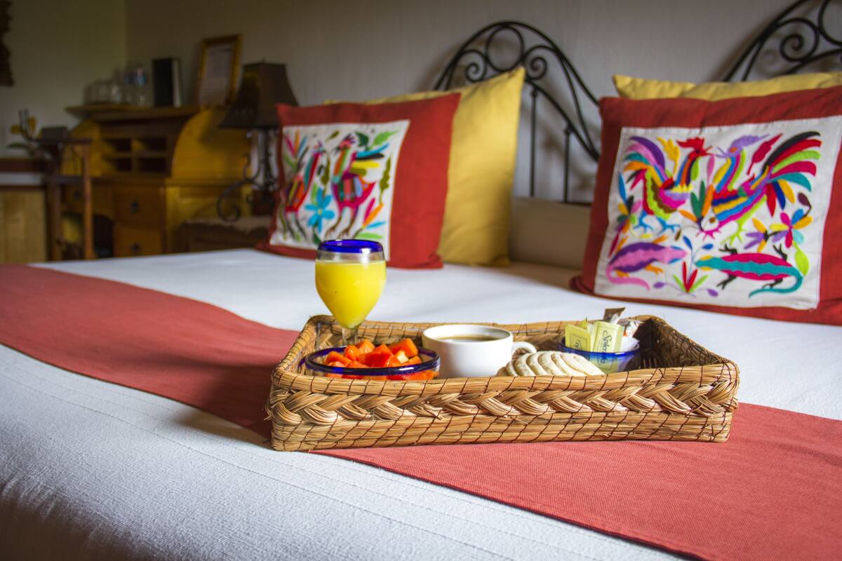 Uma cama com um tabuleiro de comida, incluindo uma bebida, petiscos e uma chávena de café.
