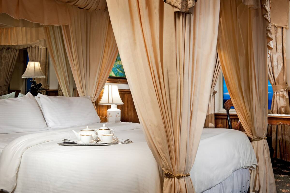 Um quarto luxuoso com uma cama grande, um serviço de chá e um criado-mudo com abajur.